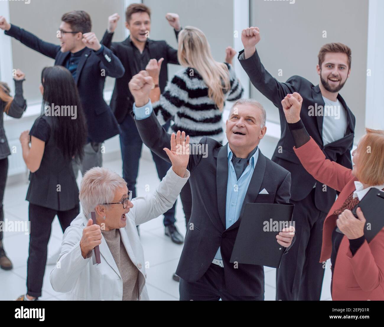 Business team celebrating a triumph with arms up in the modern office ...