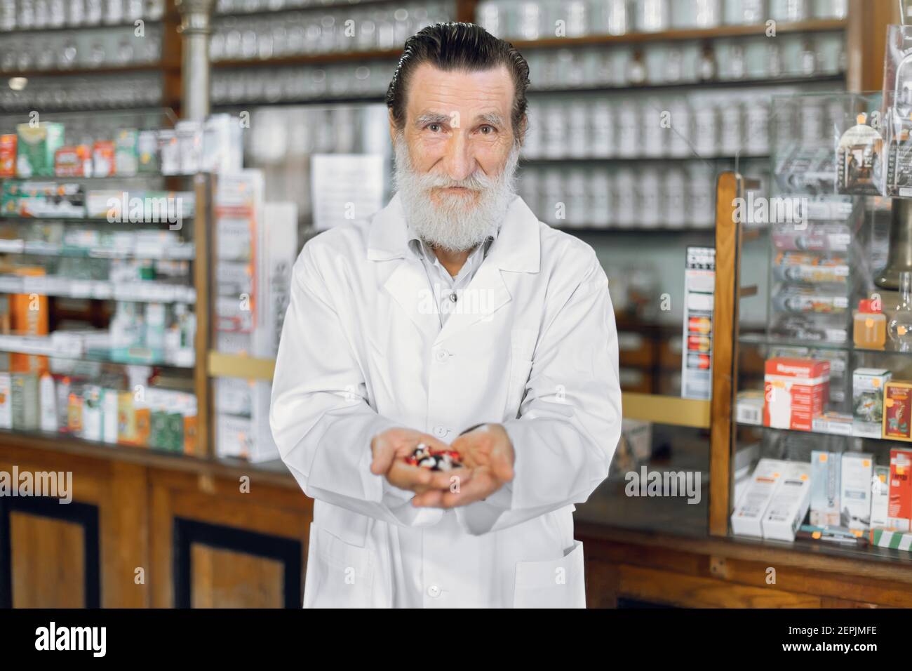 Handsome senior male pharmacist posing in ancient pharmacy interior and ...