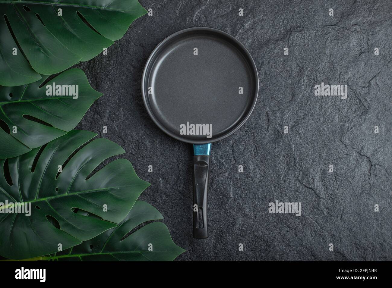 Top view of frying pan over black background with green leaves Stock ...
