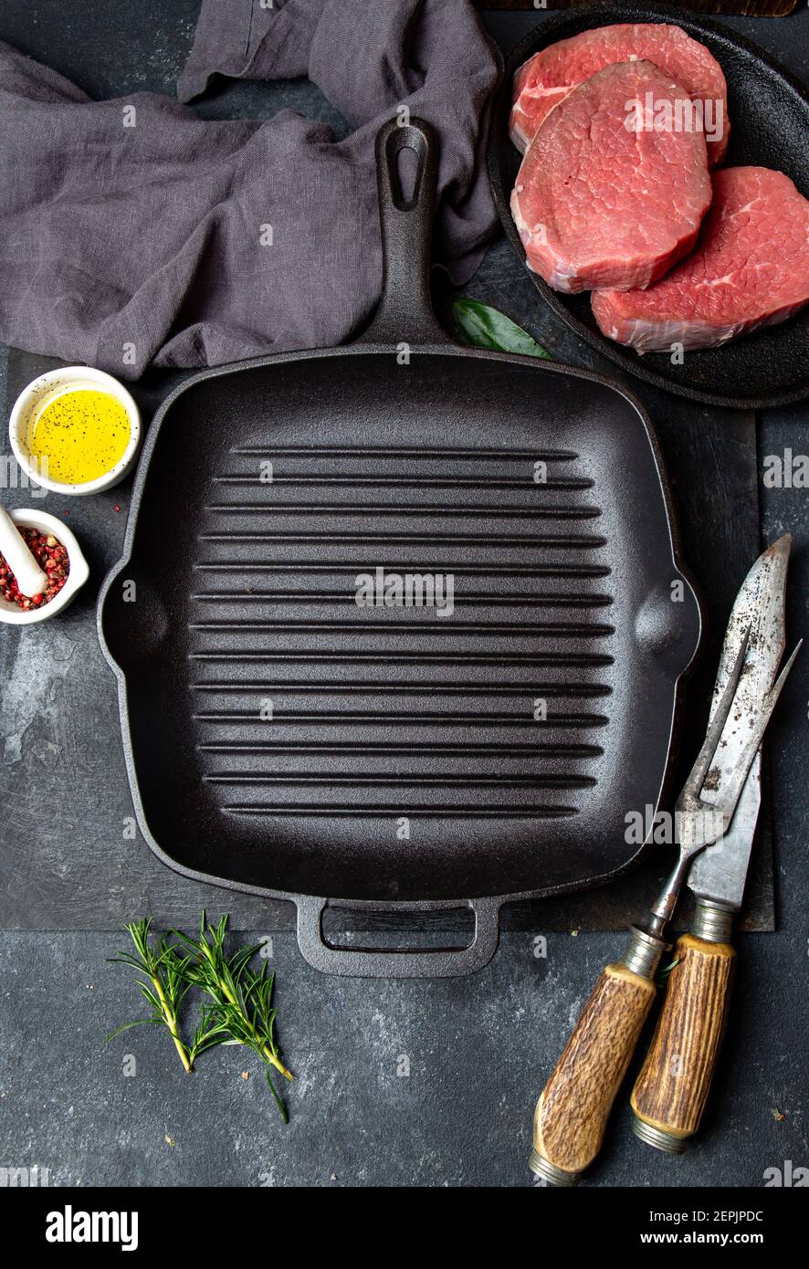 Cast Iron Grill pan, curving set, raw beef steaks and spices on black ...
