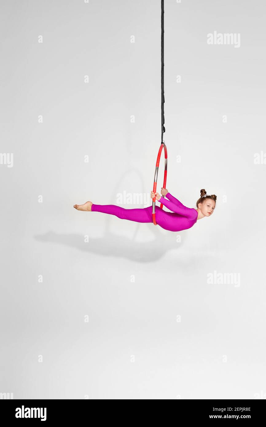little child girl gymnast in pink sportwear shows an acrobatic ...