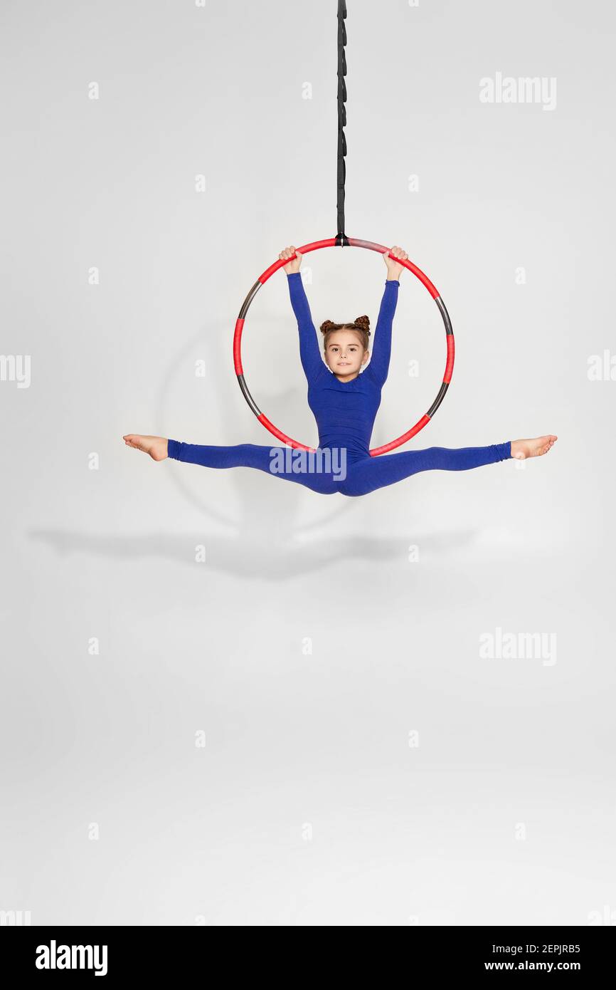 little child girl gymnast in sportwear doing twine on an aerial hoop ...