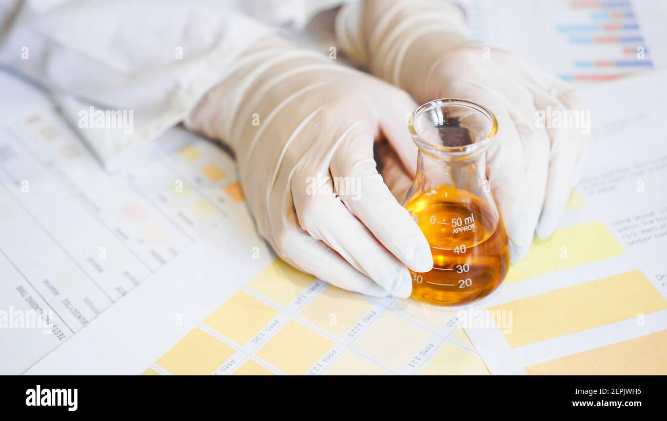 Woman making urine test with ph material in laboratory. Female hands in ...