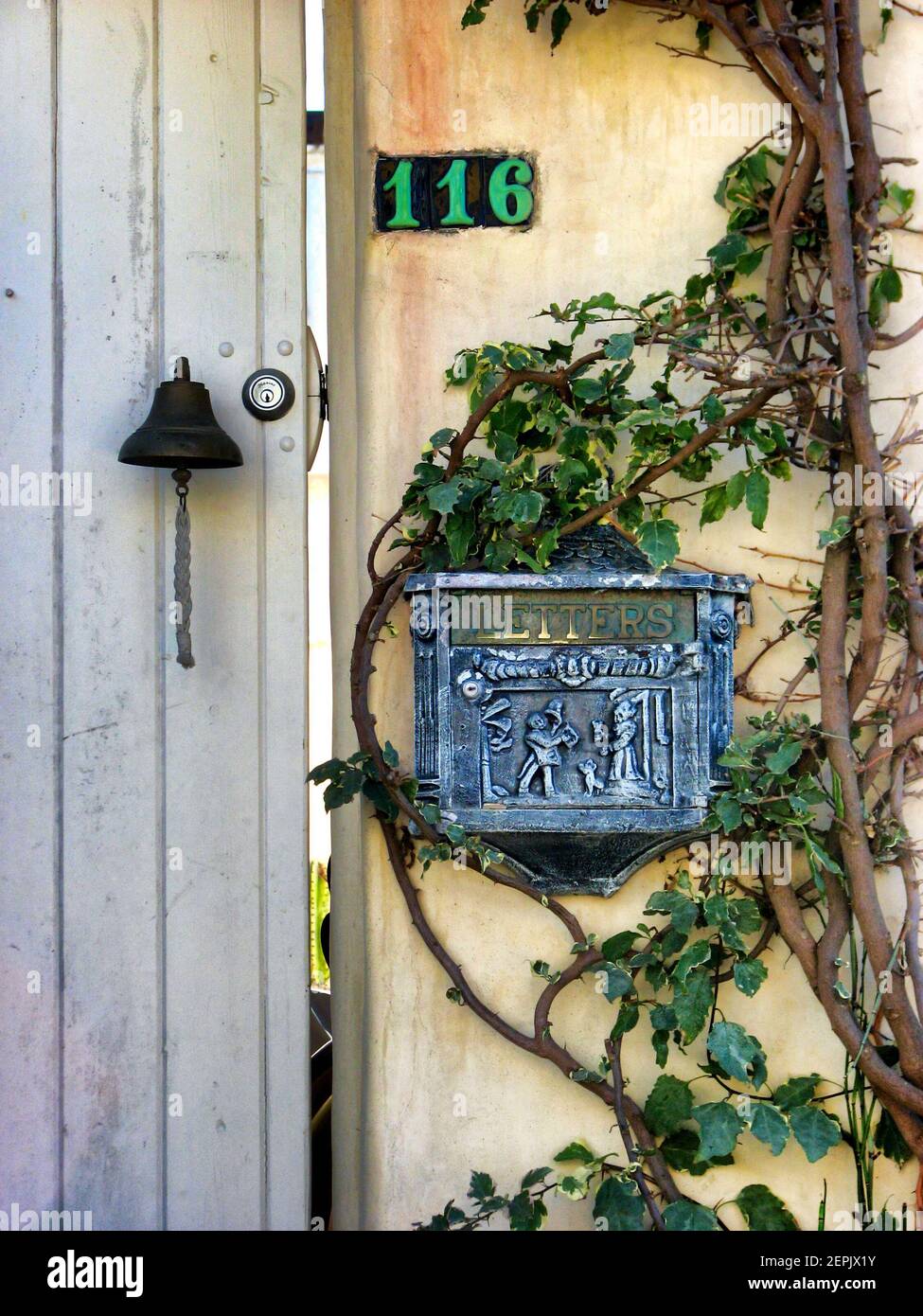 Metal antique mail box surrounded by a creeping vine at house number ...