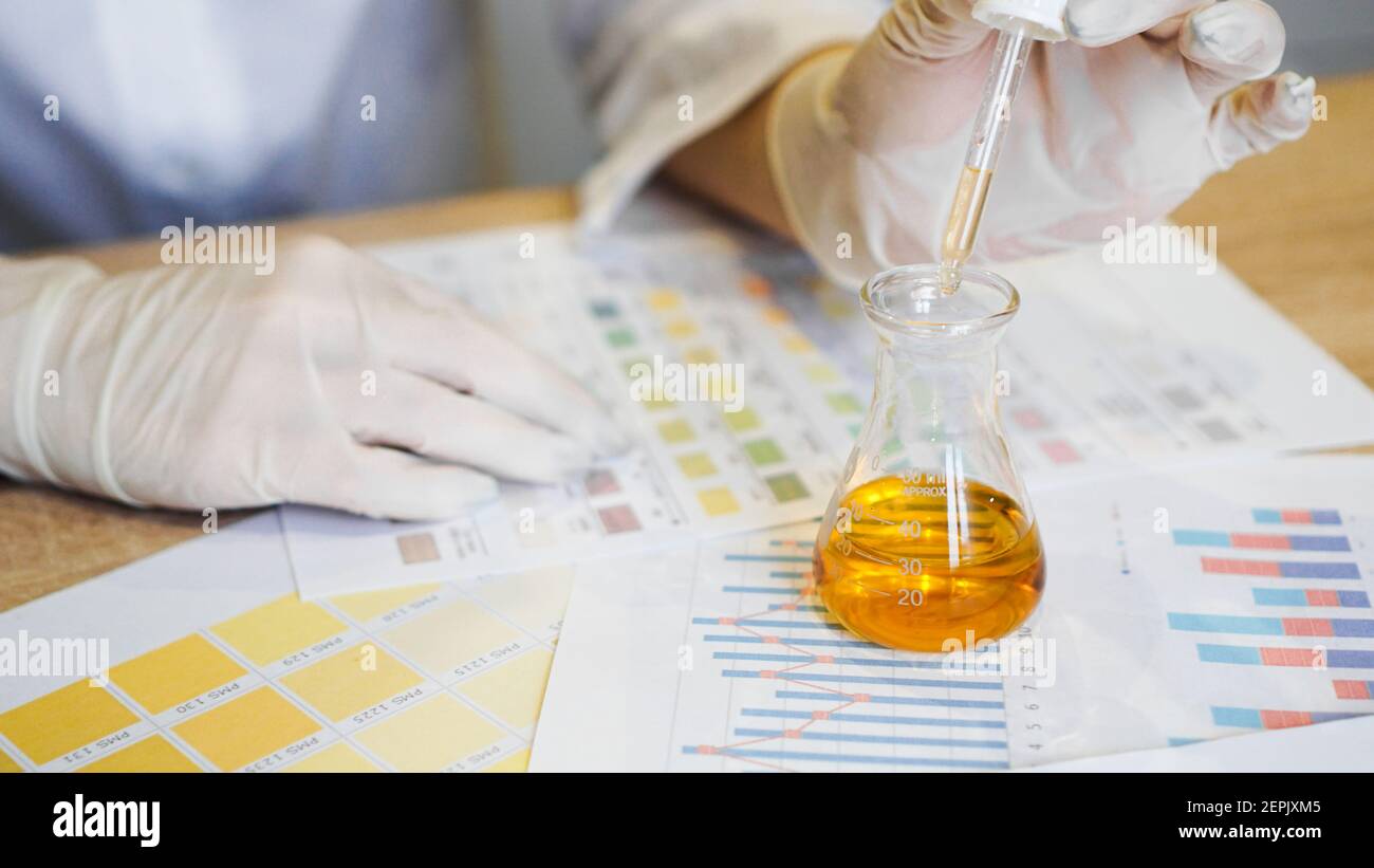 Woman making urine test with ph material in laboratory. Female hands in ...