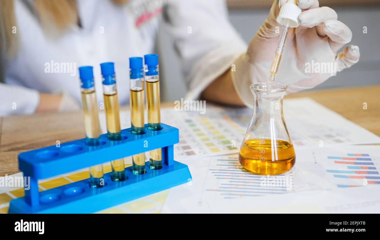 Woman making urine test with ph material in laboratory. Female hands in ...