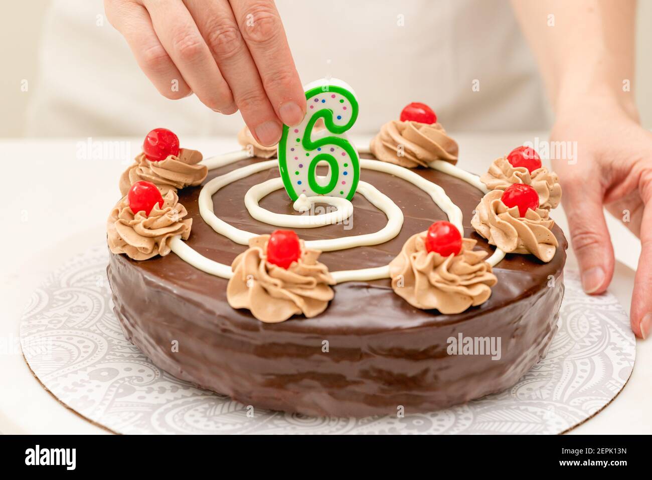 Birthday chocolate cake. Woman hands decorating cake with candle in the ...