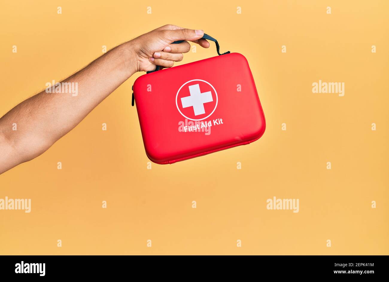 Hand of hispanic man holding first aid kit over isolated yellow ...