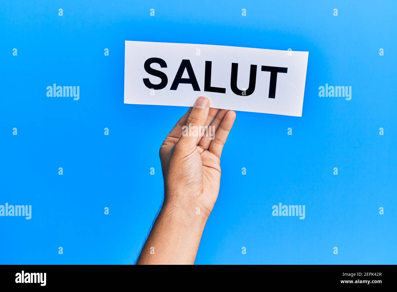 Hand of hispanic man holding salut word paper over isolated blue ...