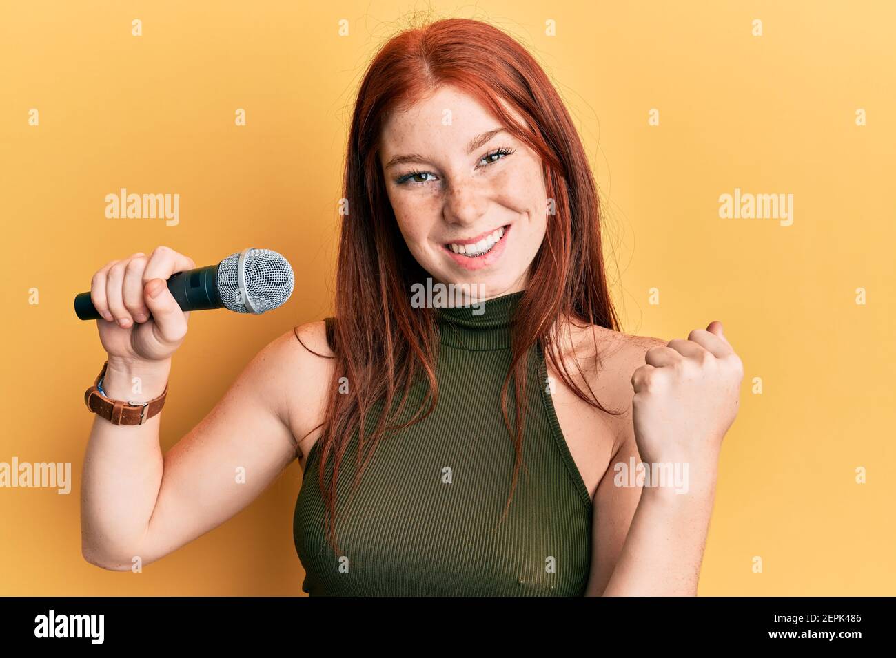 Young red head girl singing song using microphone screaming proud ...