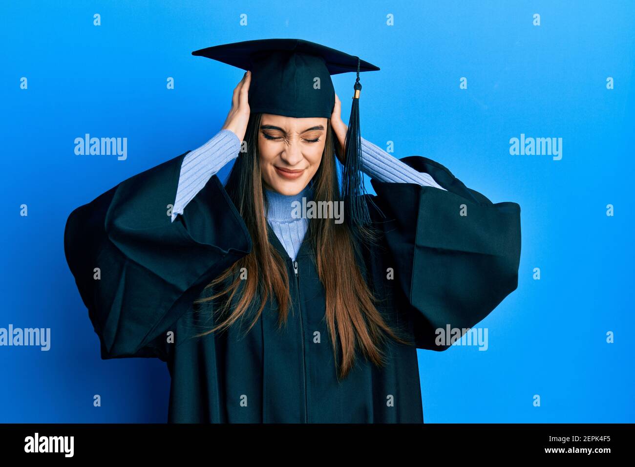Beautiful brunette young woman wearing graduation cap and ceremony robe ...
