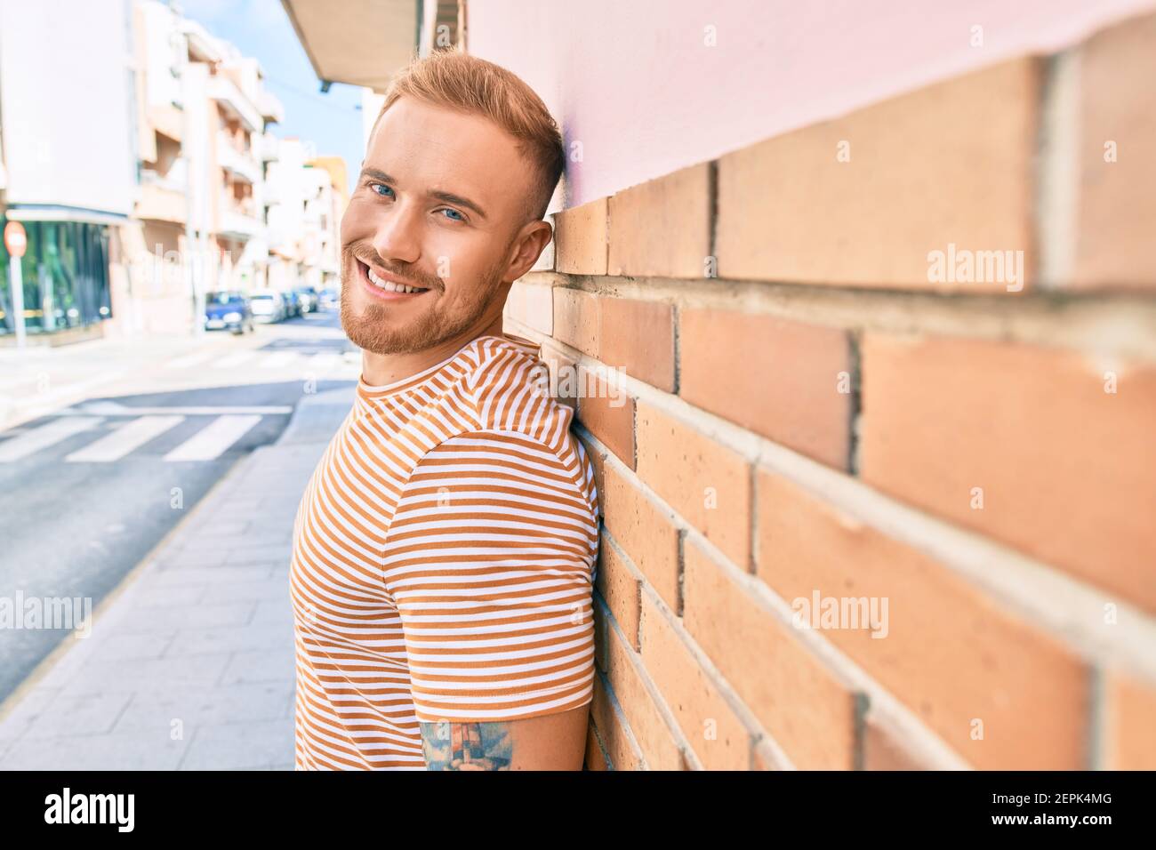 Young irish man smiling happy leaning on the wall at street of city ...