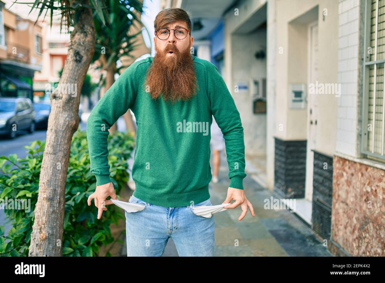 Young irish man with sad expression showing his empty pockets jeans at ...