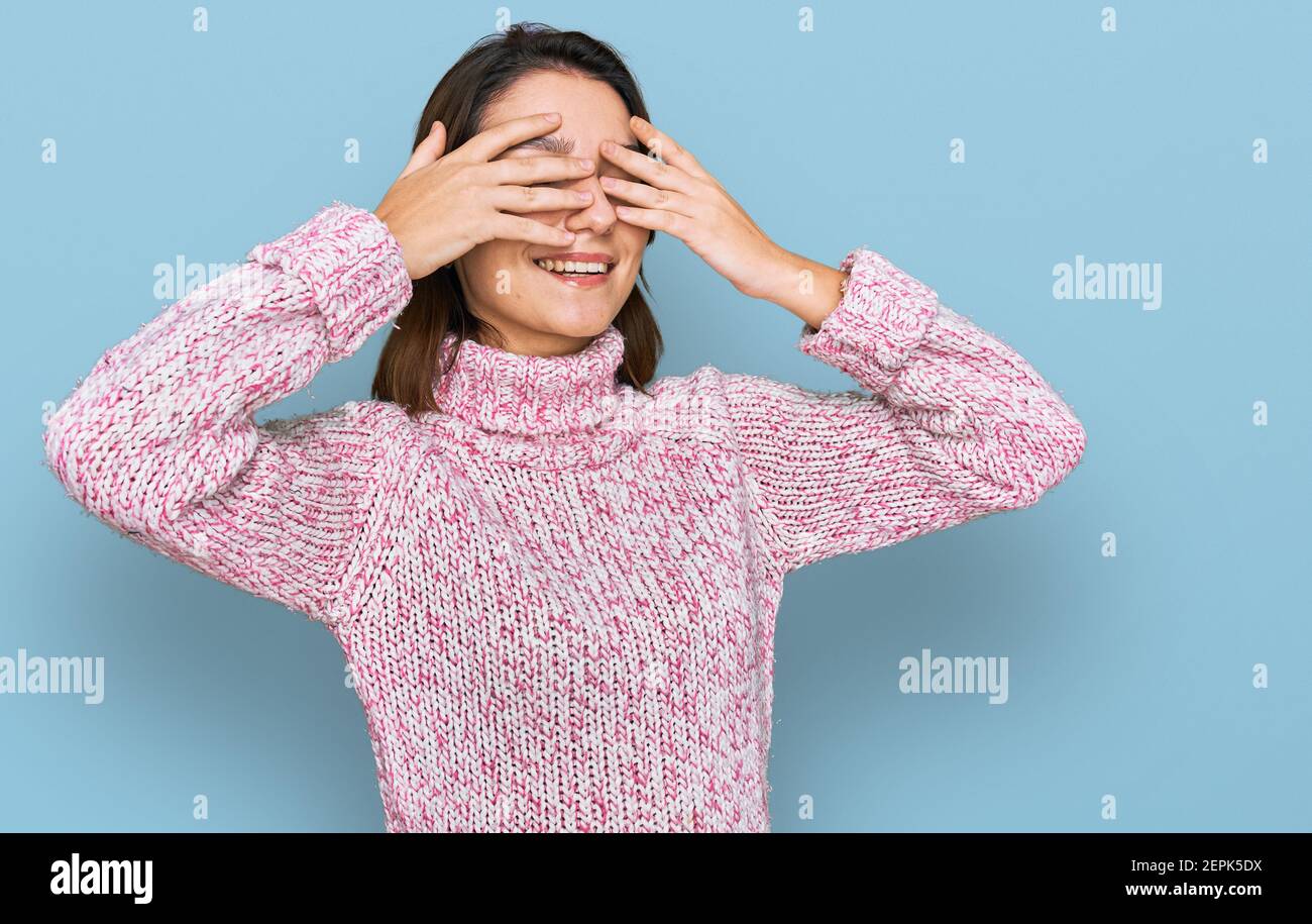 Young caucasian girl wearing wool winter sweater covering eyes with ...