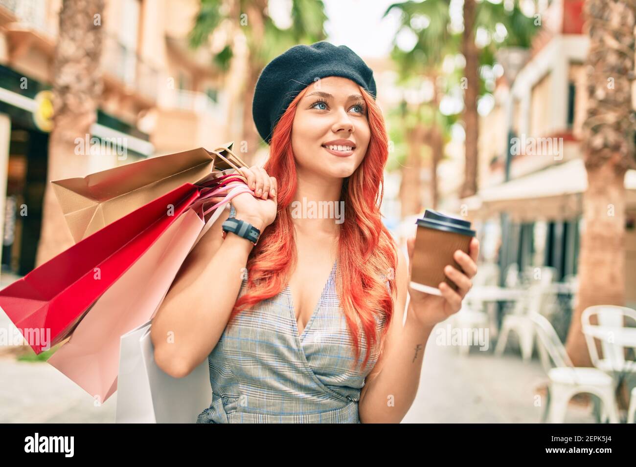 Young redhead girl wearing french style holding shopping bags and ...