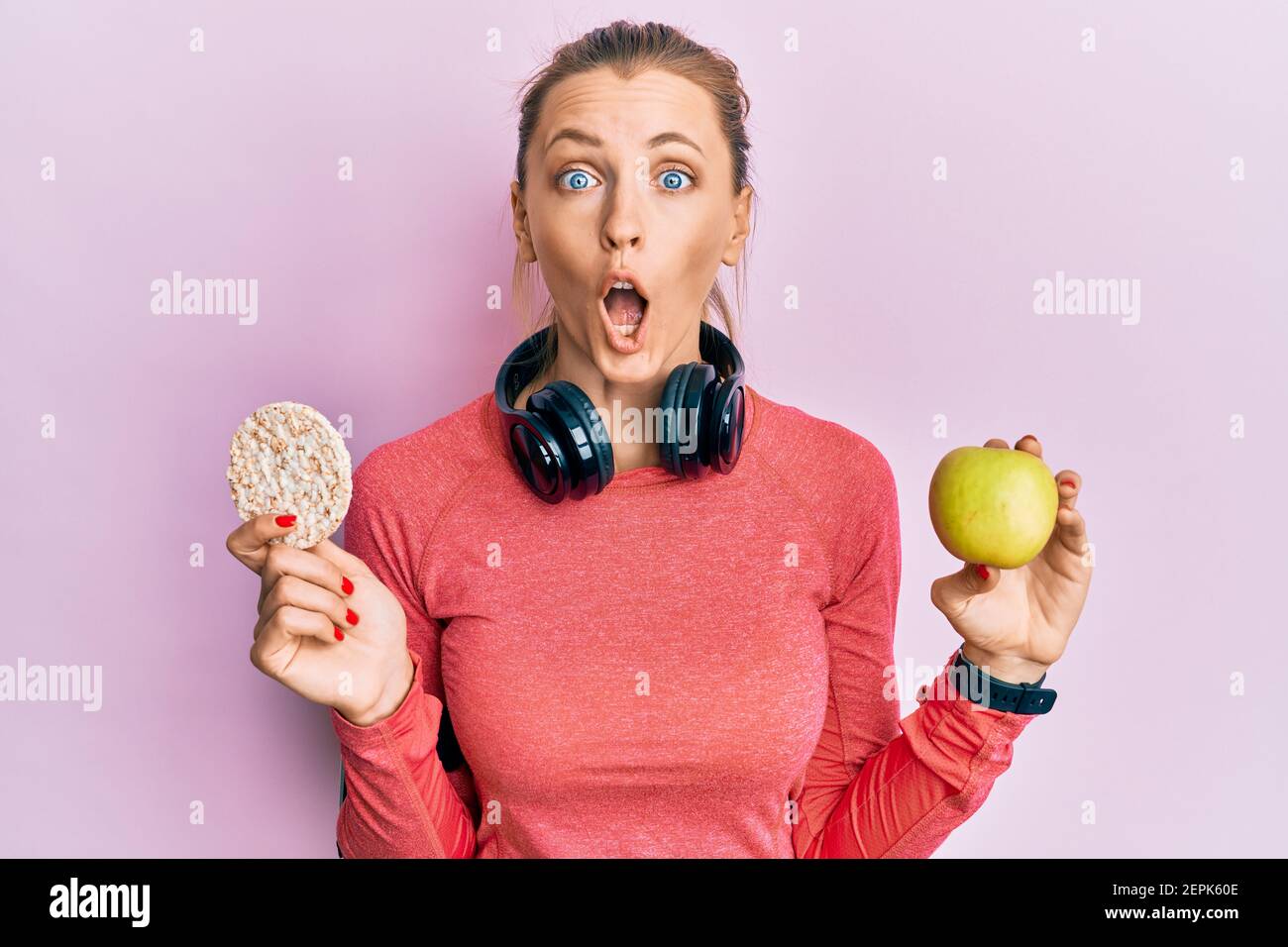 Beautiful caucasian sports woman holding green apple and rice crackers ...