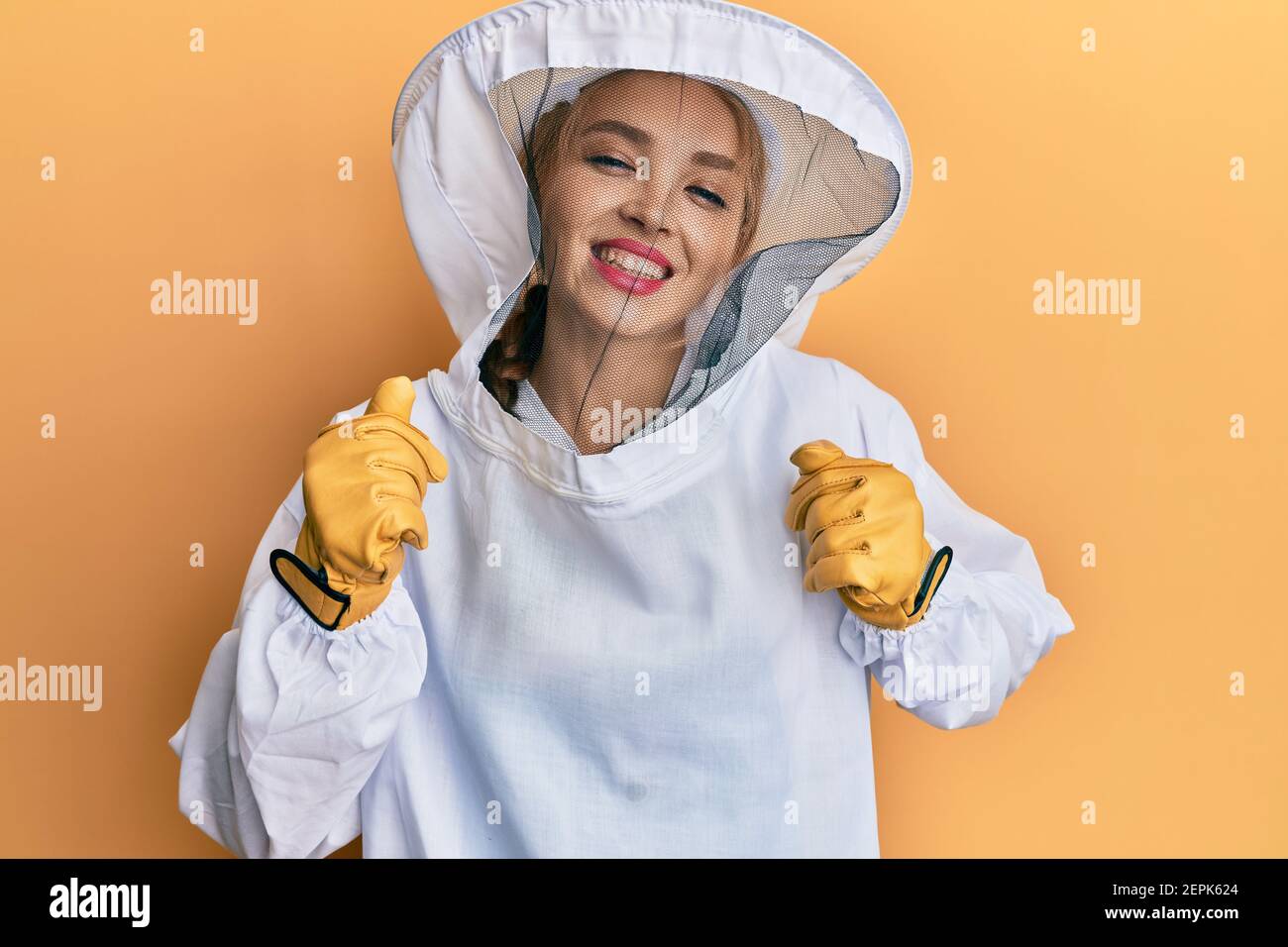 Beautiful blonde caucasian woman wearing protective beekeeper uniform ...