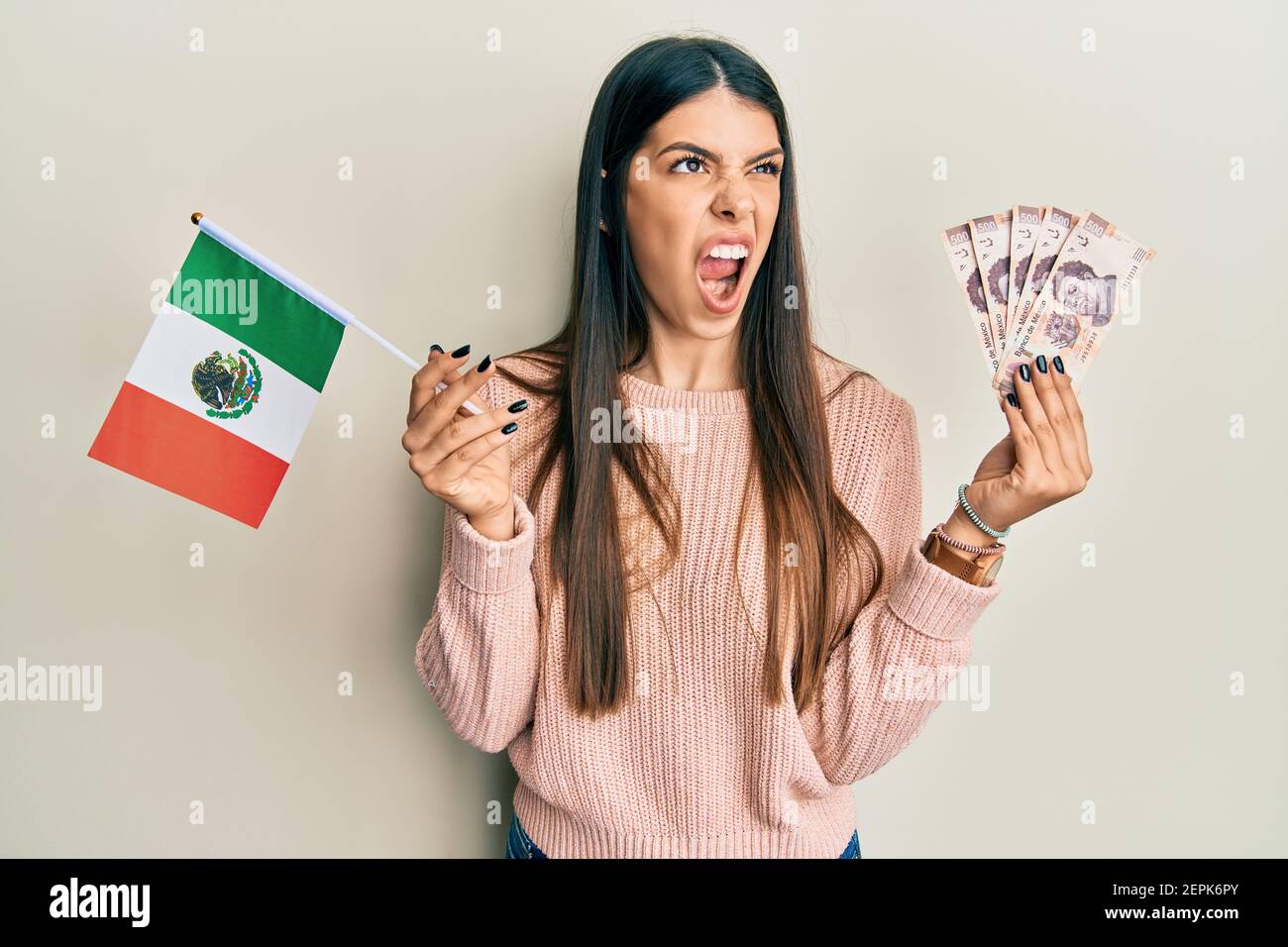 Young hispanic woman holding mexico flag and mexican pesos banknotes ...