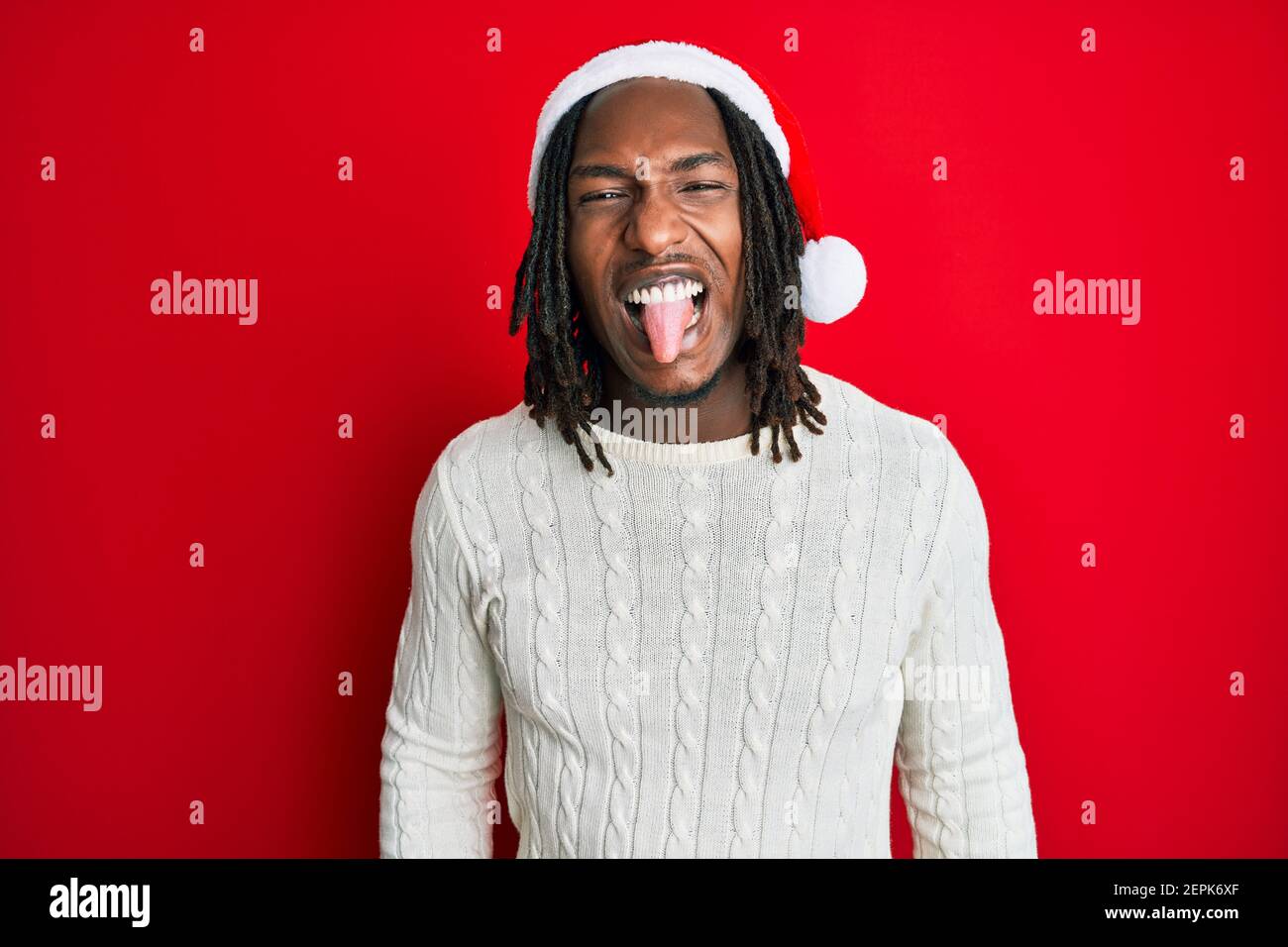 African american man with braids wearing christmas hat sticking tongue ...
