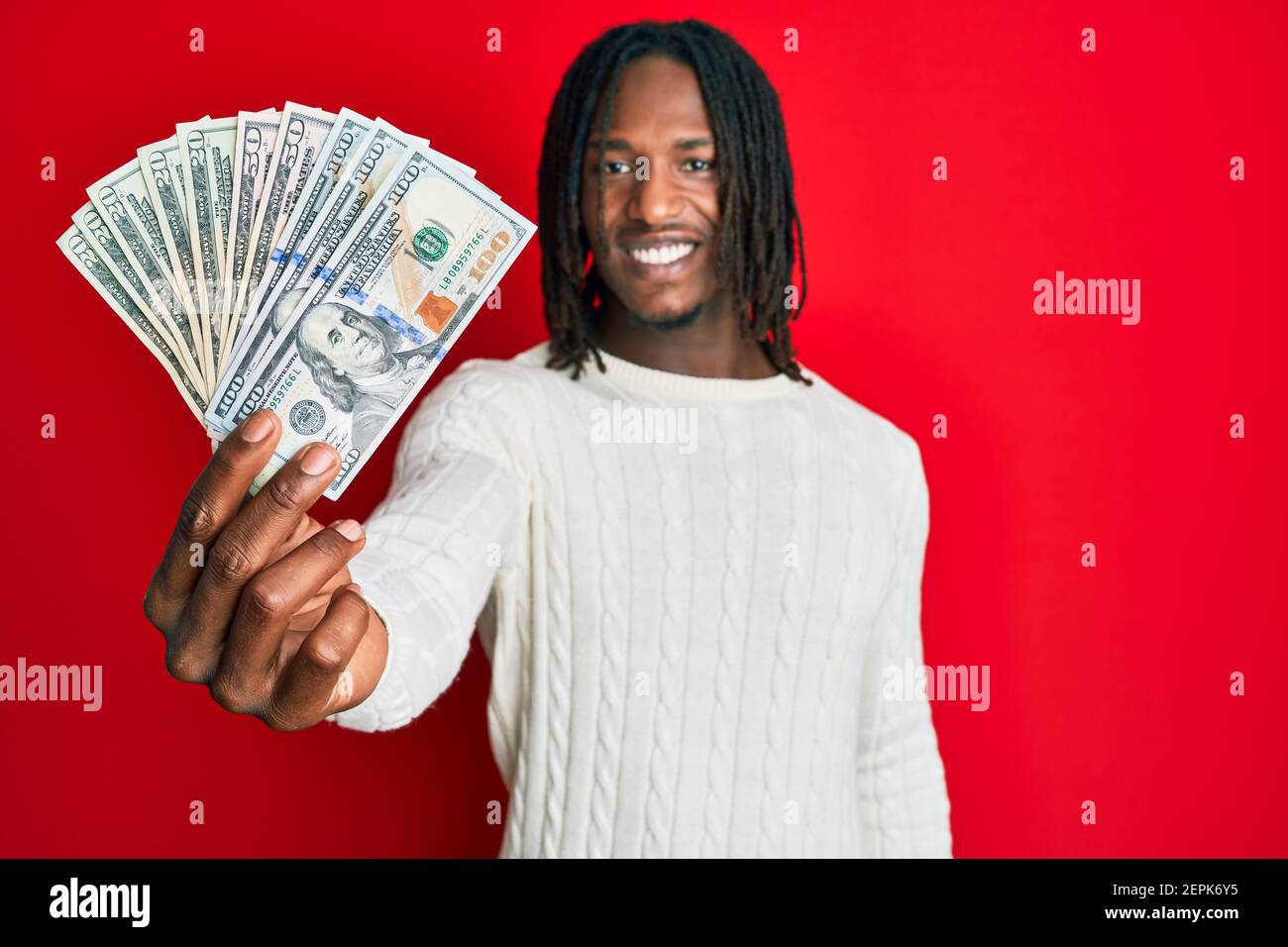 African american man with braids holding dollars looking positive and ...