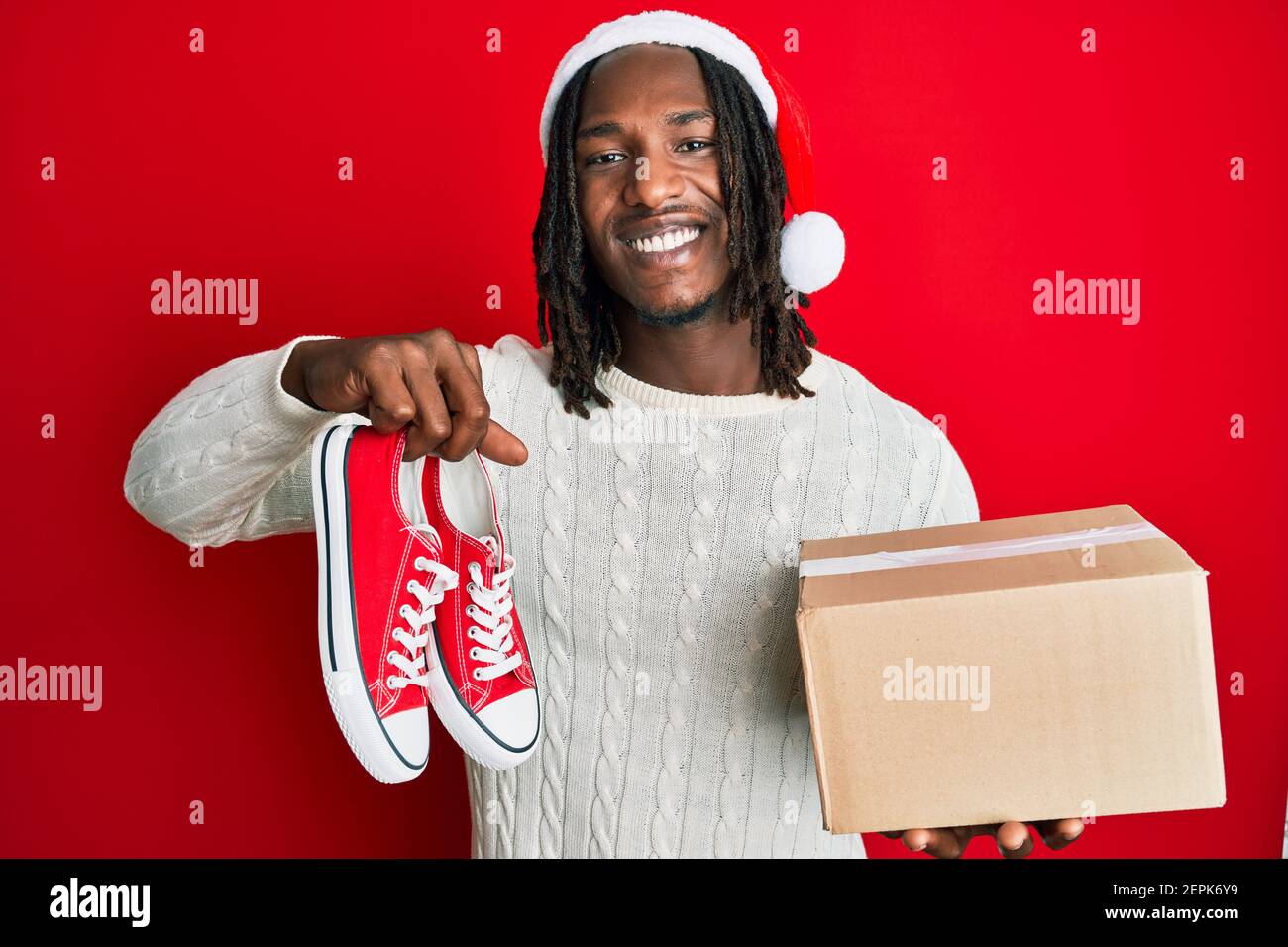 African american man with braids wearing christmas hat having shoes as ...