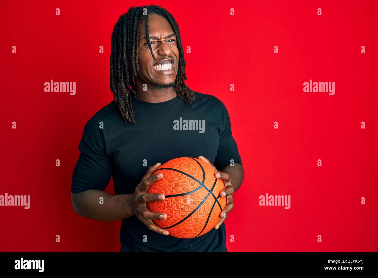 African american man with braids holding basketball ball angry and mad ...