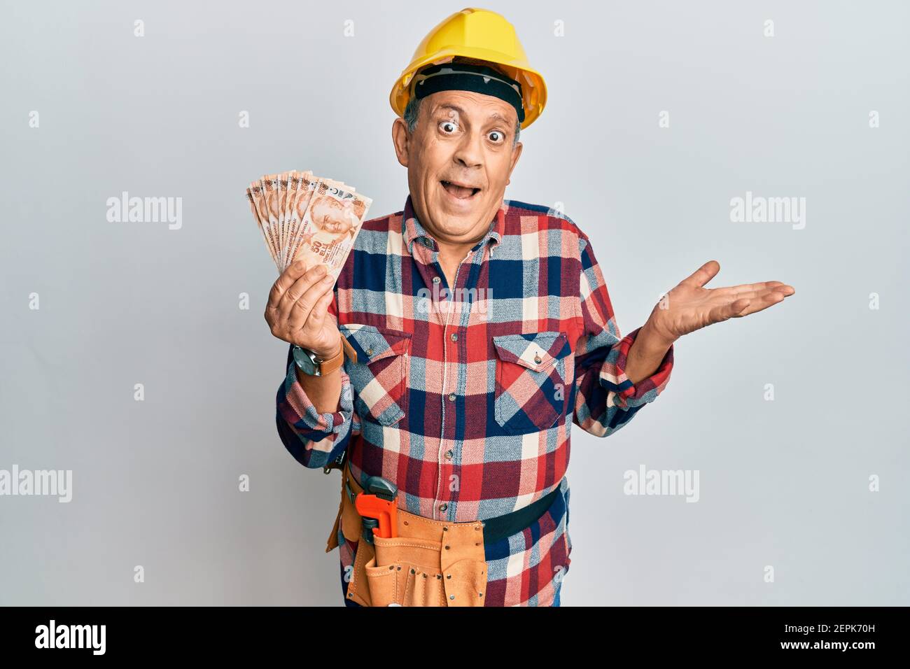 Senior hispanic man wearing handyman uniform holding turkish liras ...