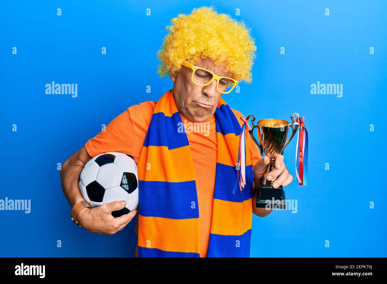 Senior hispanic man football hooligan cheering game holding ball and ...