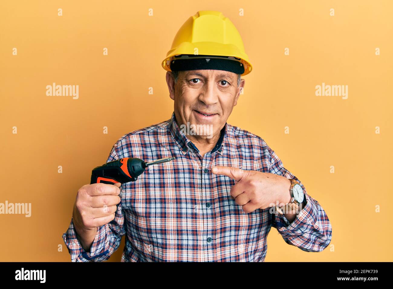 Handsome senior man with grey hair holding screwdriver wearing hardhat ...