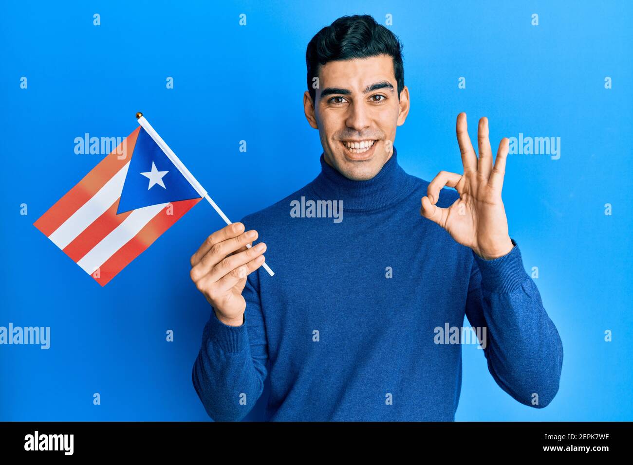 Handsome hispanic man holding puerto rico flag doing ok sign with ...
