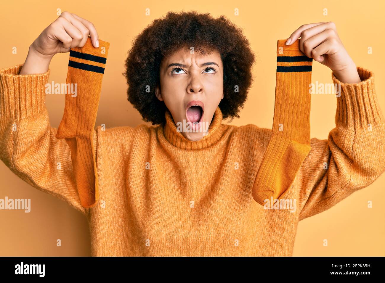 Young hispanic girl holding pair of socks angry and mad screaming ...