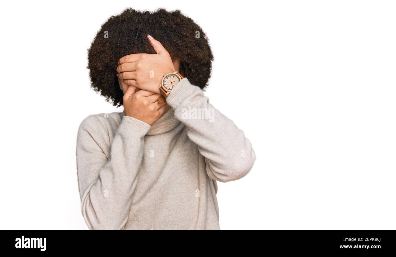 Young hispanic girl wearing wool winter sweater covering eyes and mouth ...