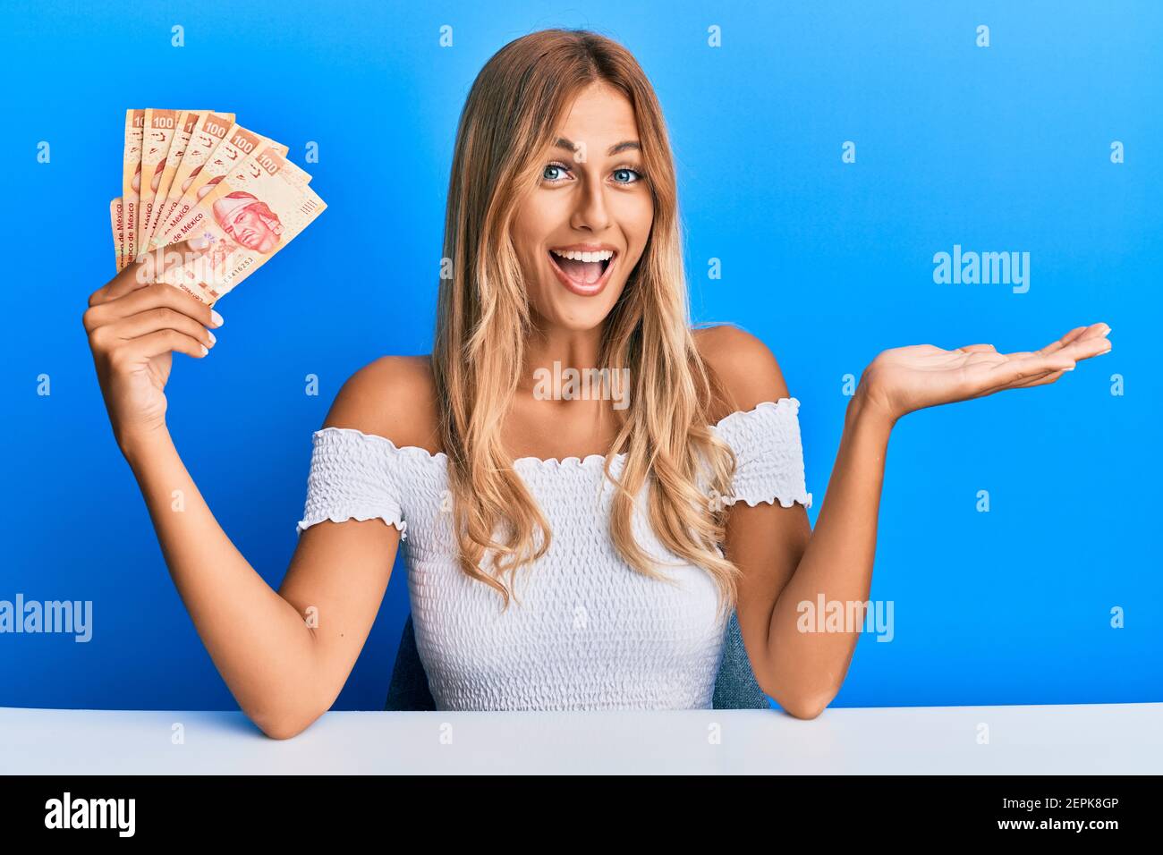 Beautiful blonde young woman holding 100 mexican pesos banknotes ...