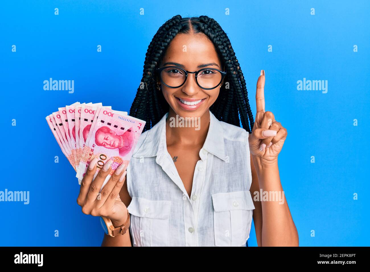 Beautiful hispanic woman holding 100 yuan chinese banknotes smiling ...