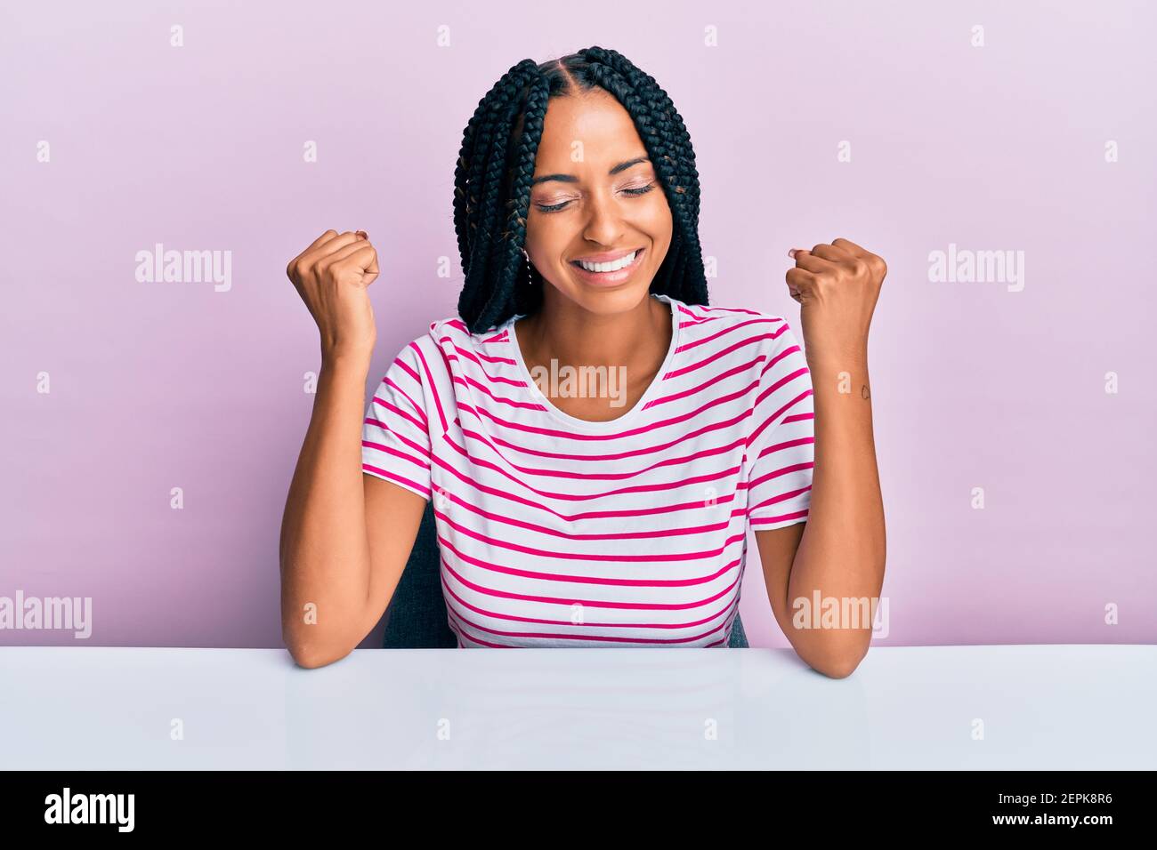 Beautiful hispanic woman wearing casual clothes sitting on the table ...