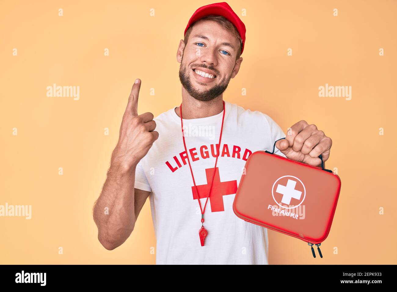 Young caucasian man wearing lifeguard t shirt holding first aid kit ...