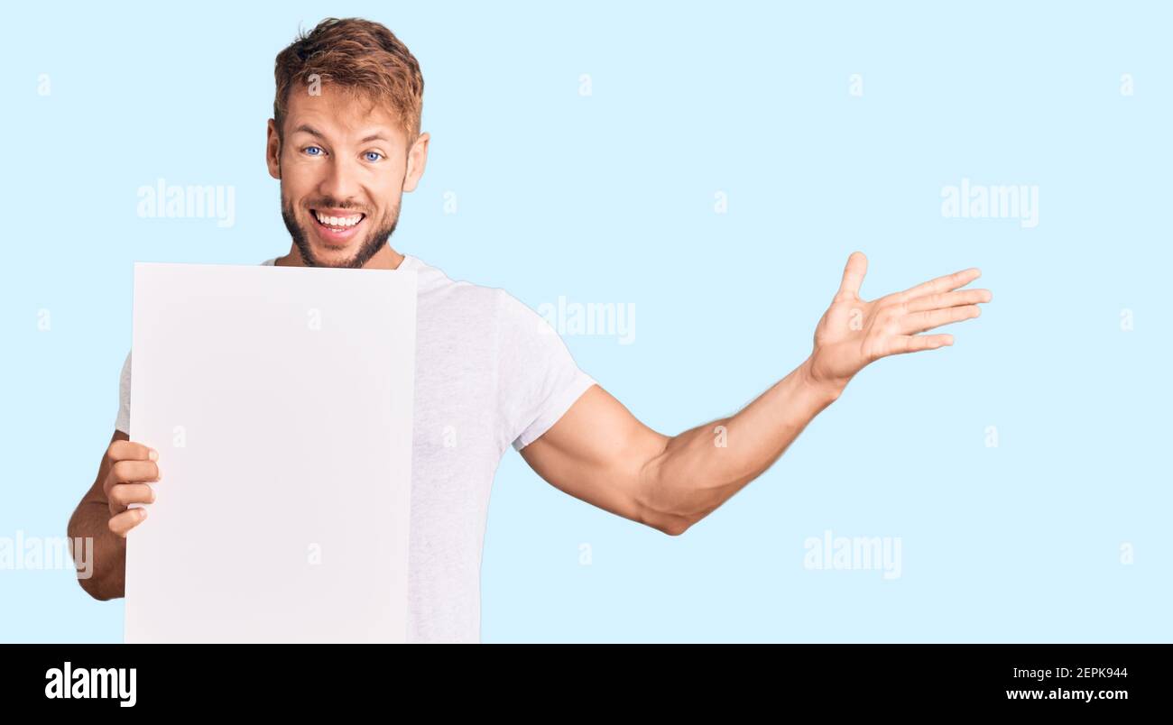 Young caucasian man holding blank empty banner celebrating victory with ...