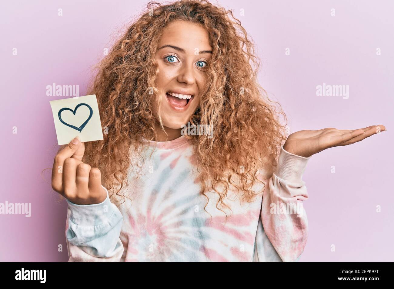 Beautiful caucasian teenager girl holding heart reminder celebrating ...