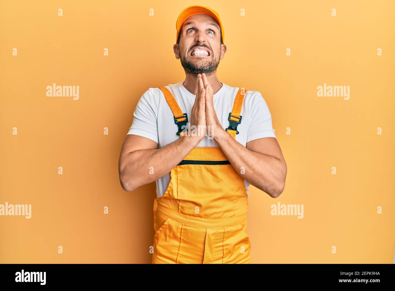 Young handsome man wearing handyman uniform over yellow background ...