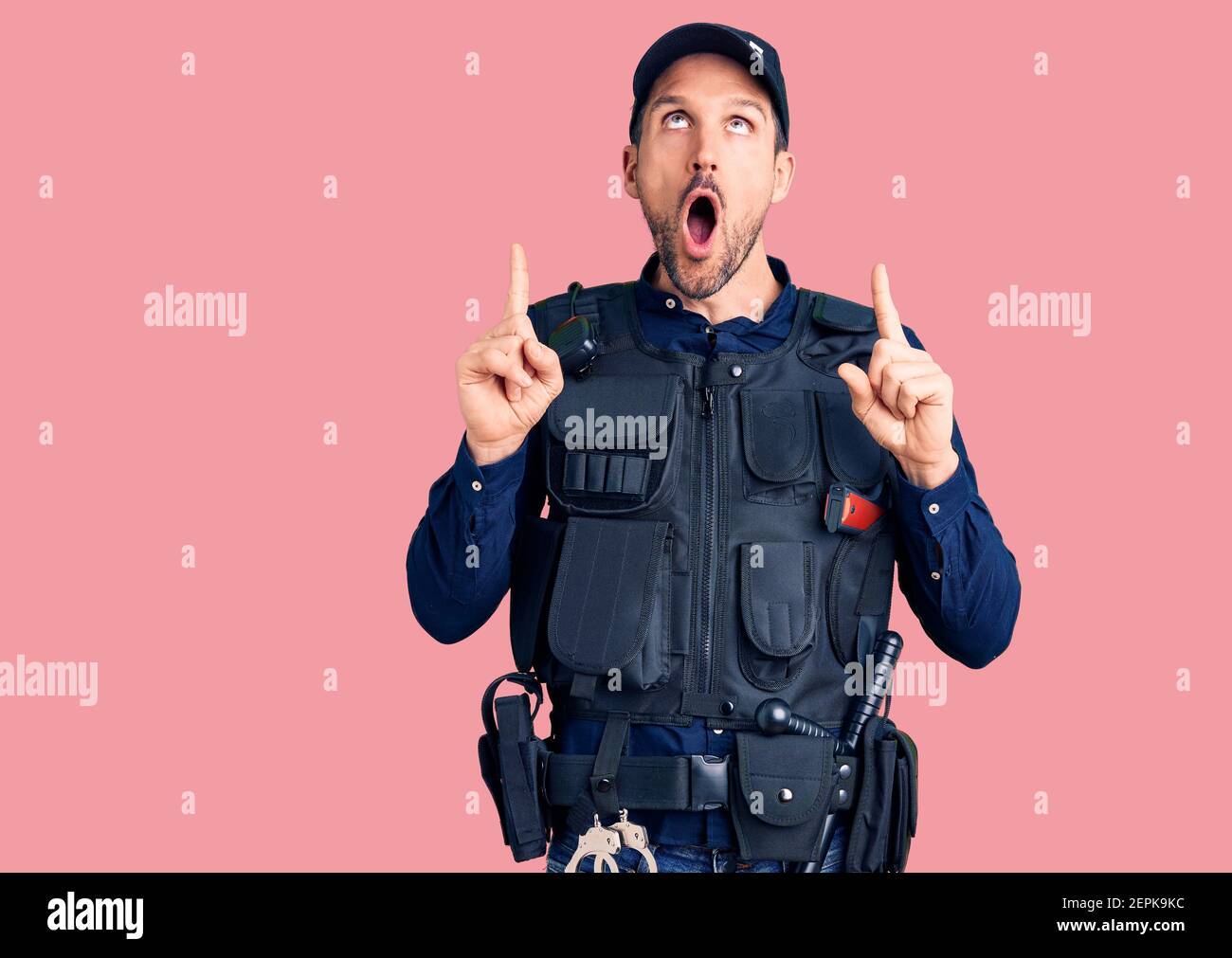 Young handsome man wearing police uniform amazed and surprised looking ...