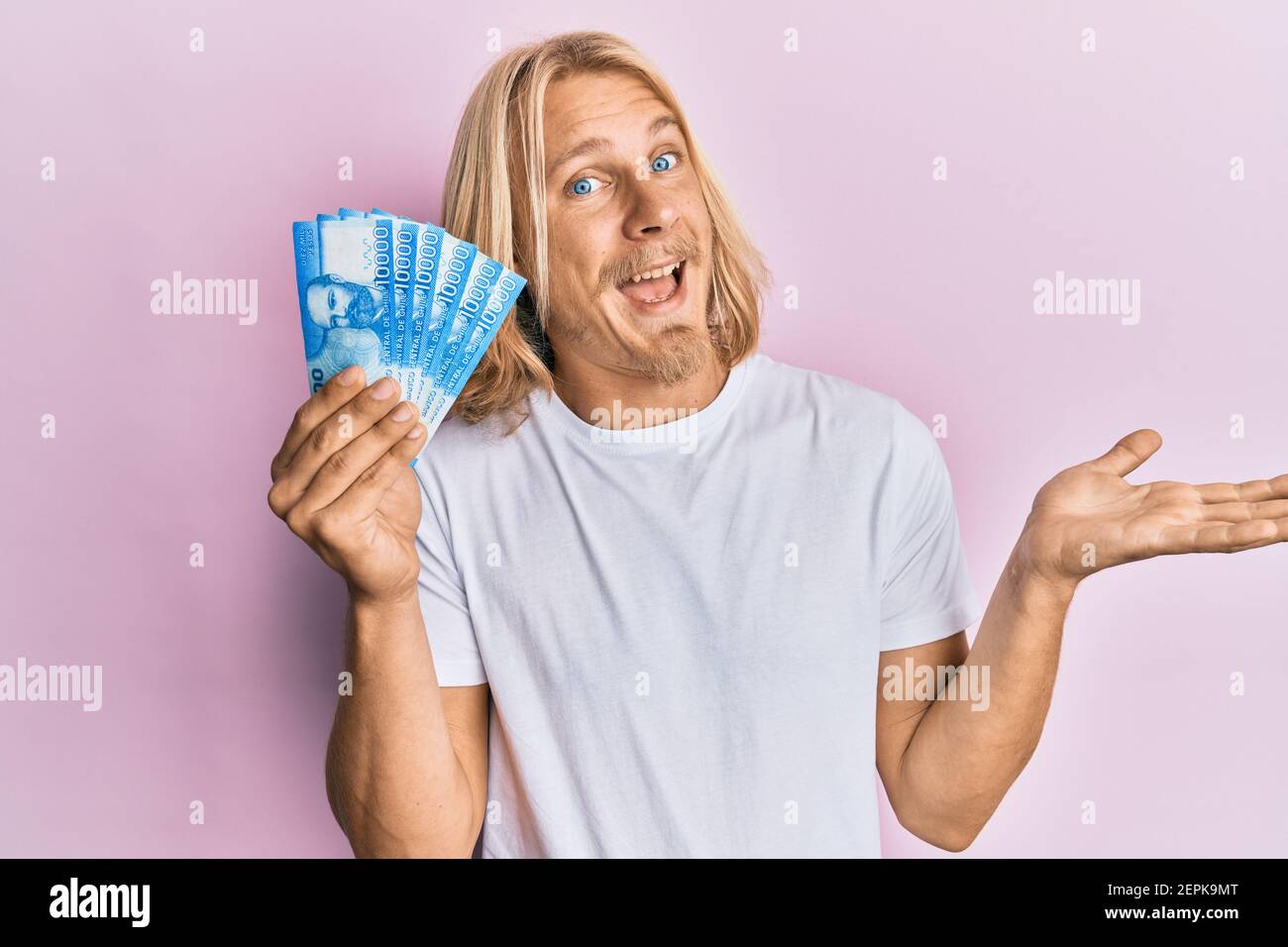 Caucasian young man with long hair holding 10000 chilean pesos ...