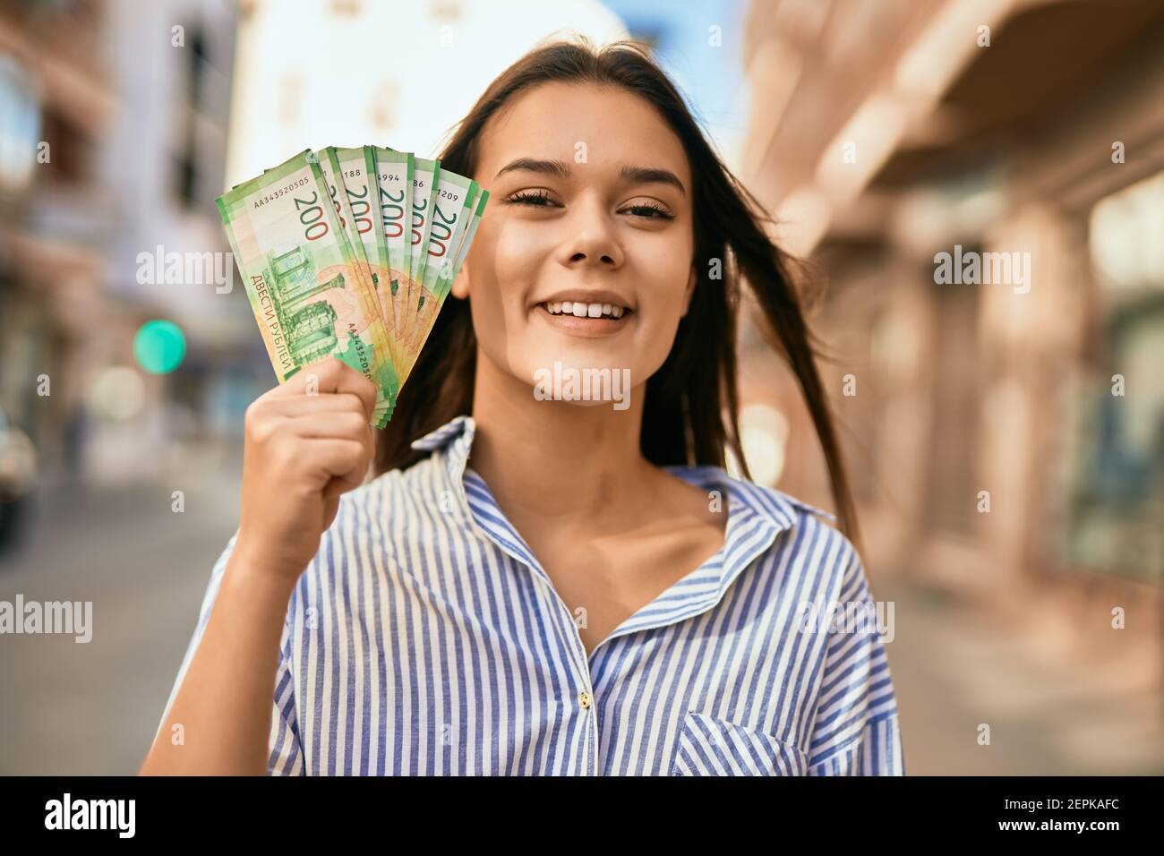 Young hispanic girl smiling happy holding russian ruble banknotes at ...