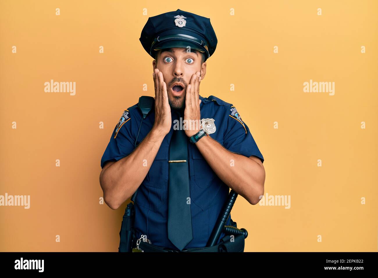 Handsome hispanic man wearing police uniform afraid and shocked ...