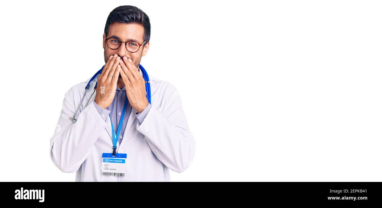 Young hispanic man wearing doctor uniform and stethoscope laughing and ...