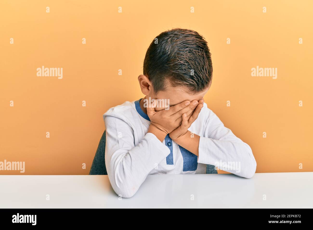 Adorable caucasian kid wearing casual clothes sitting on the table with ...