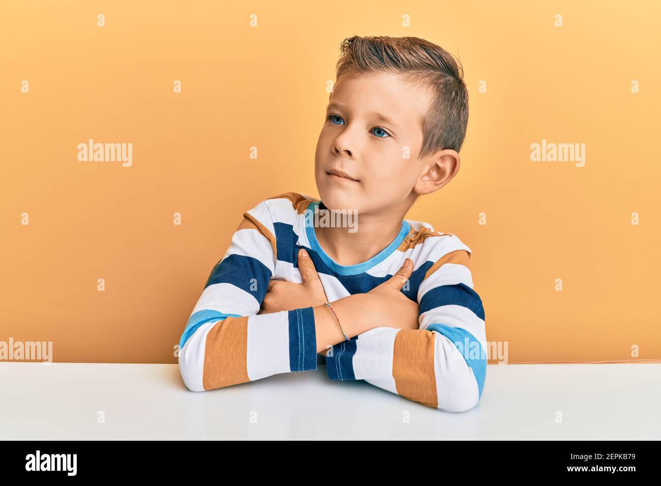 Adorable caucasian kid wearing casual clothes sitting on the table ...