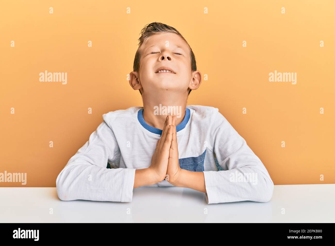 Adorable caucasian kid wearing casual clothes sitting on the table ...