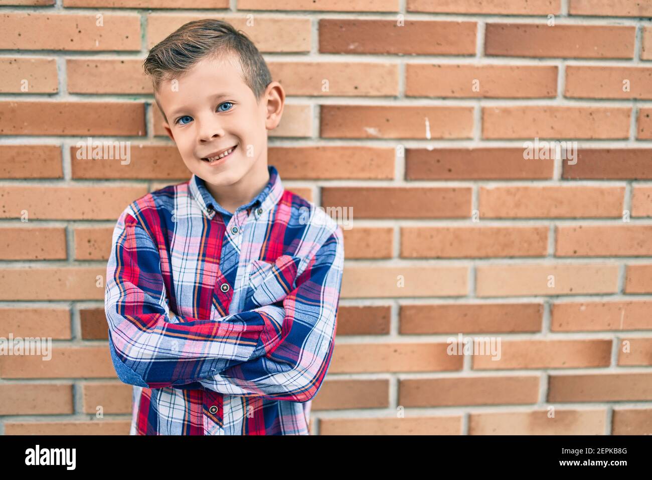 Adorable caucasian boy with crossed arms smiling happy leaning on the ...