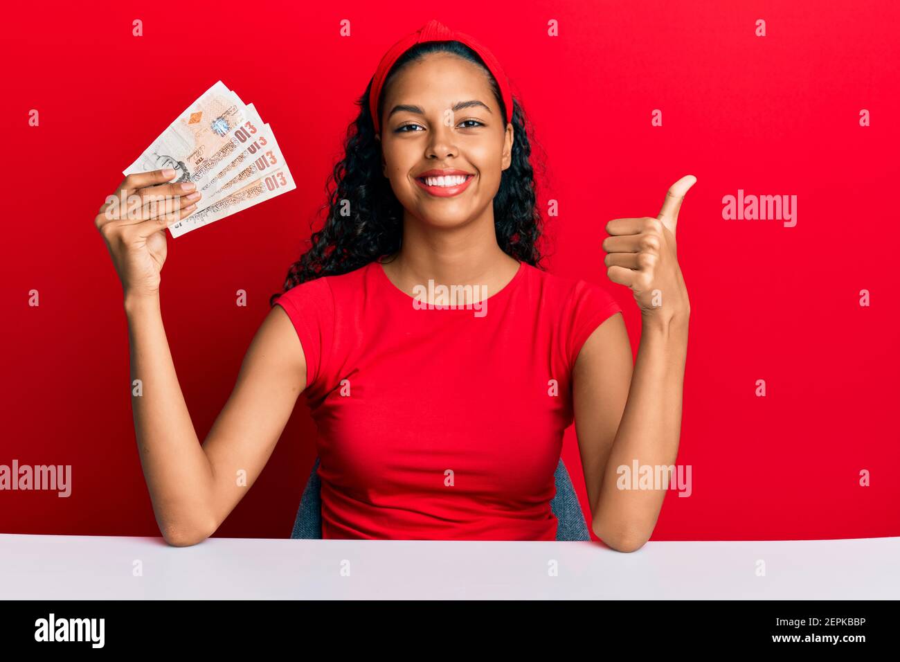 Young african american girl holding united kingdom pounds sitting on ...