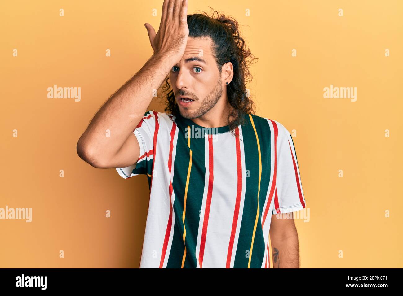 Young handsome man with long hair wearing casual clothes surprised with ...